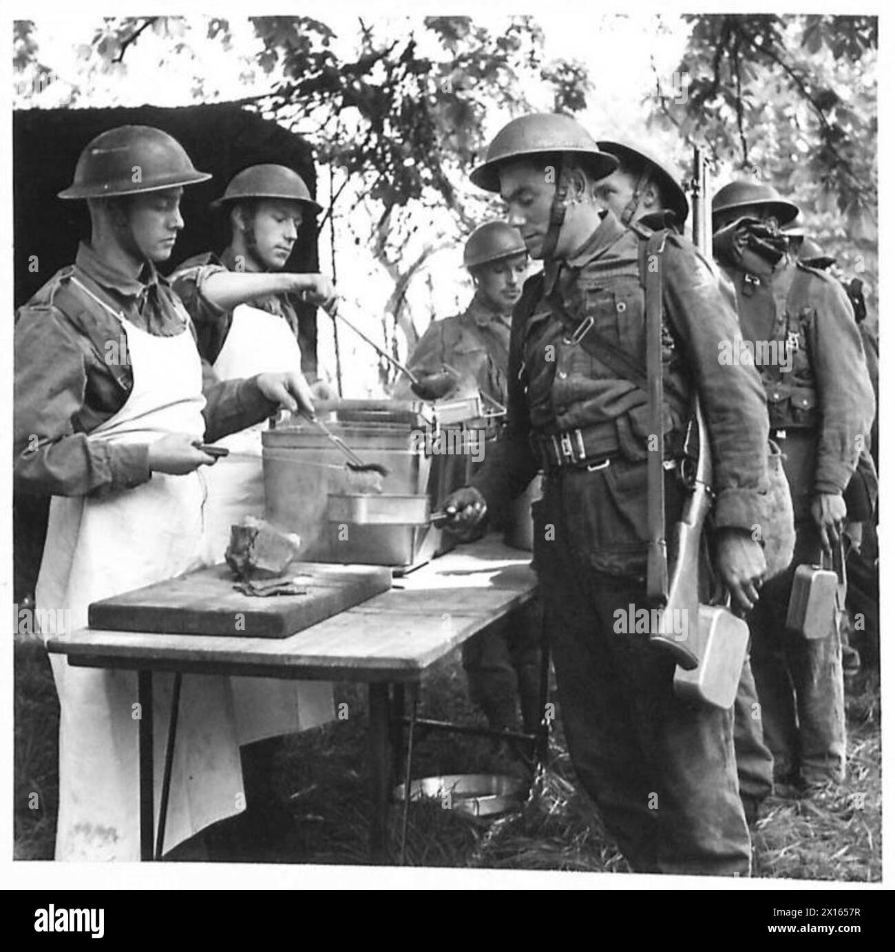Army personnel are shown receiving rations at a field kitchen operated ...