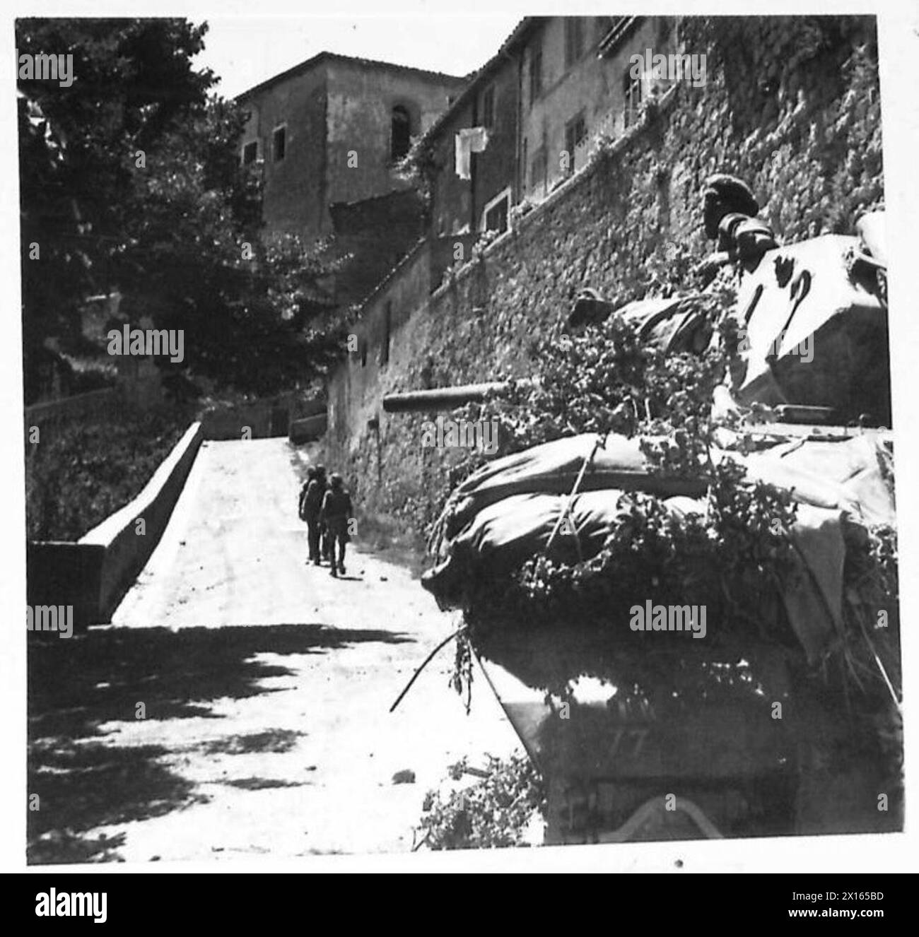 Infantry move up a street in Montepulciano covered by a South African tank destroyer as part of ...