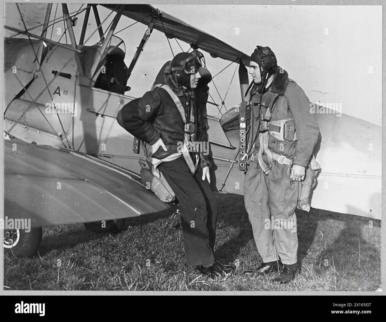 An RAF instructor and pupil discuss a Tiger Moth training flight at an ...