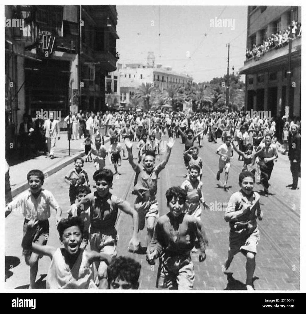 Children run down a side street to watch the entry of British troops ...