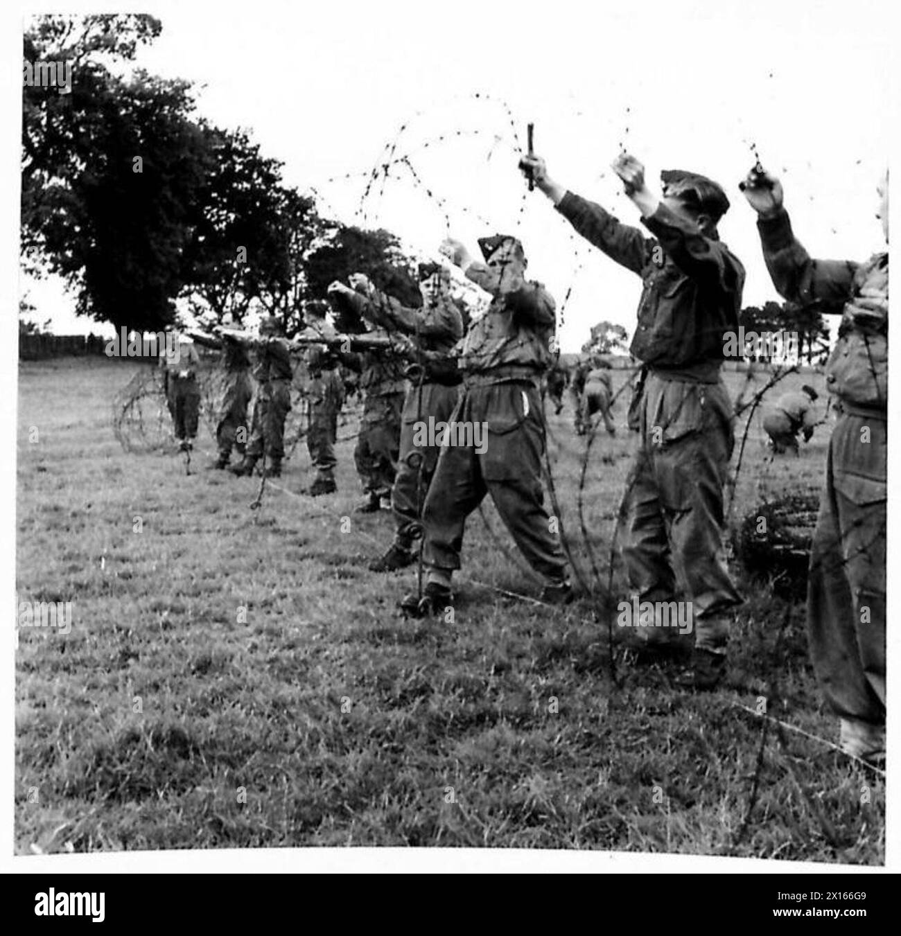 RAF personnel lay triple concertina Dannert wiring, lifting it over and ...