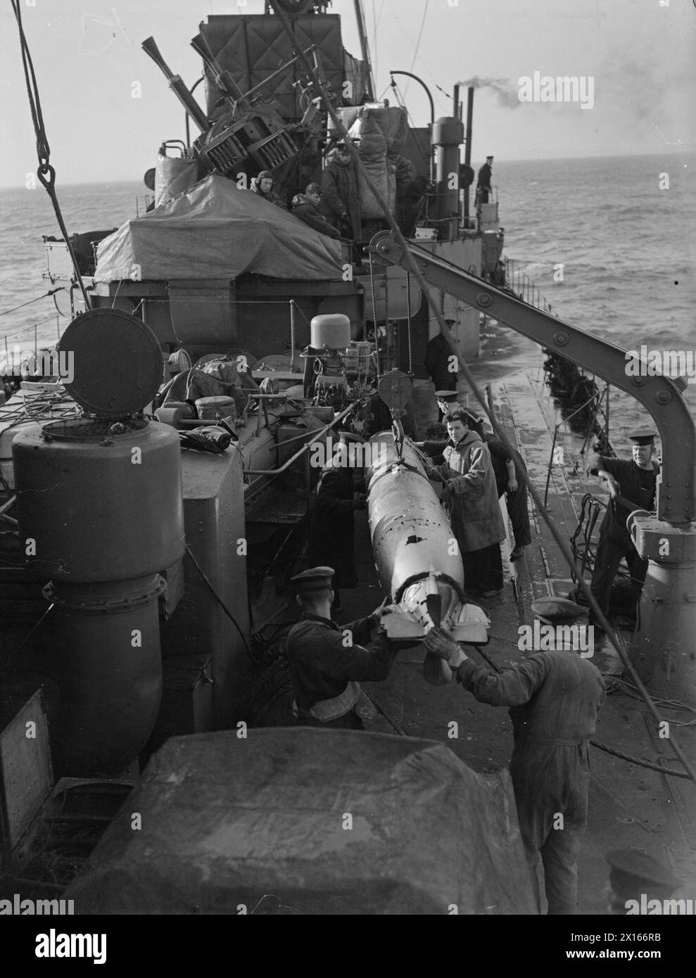 Sailors on board the destroyer HMS Cossack perform torpedo handling ...