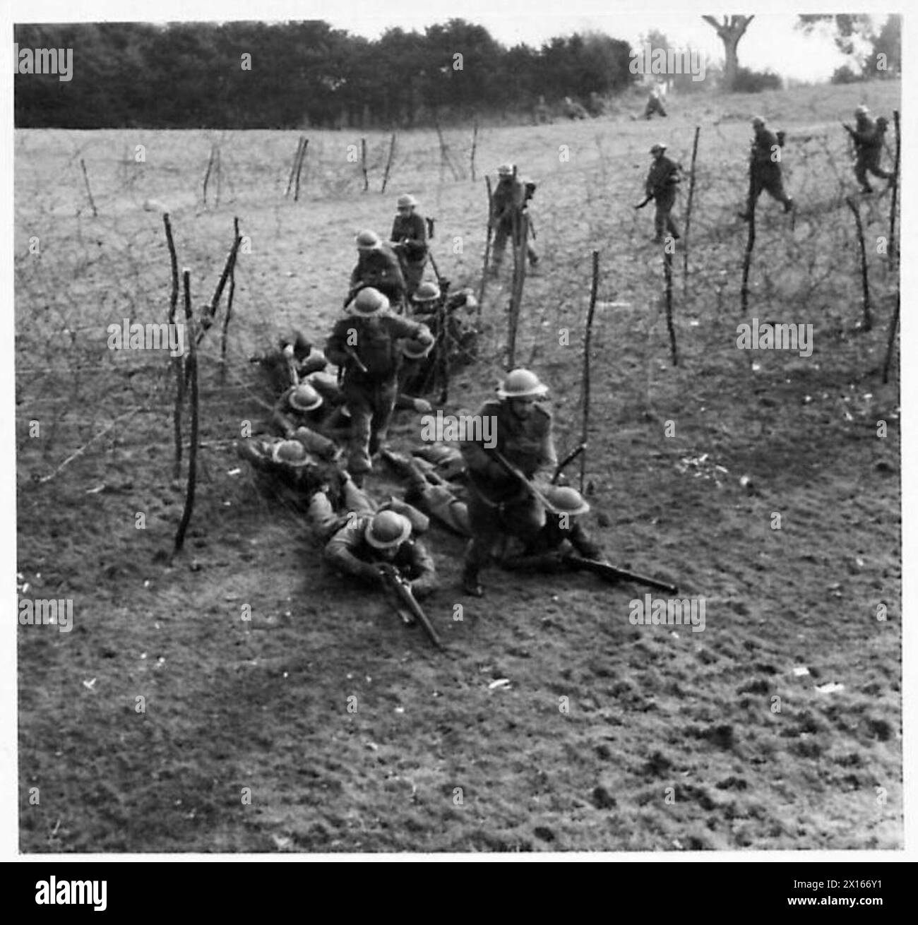 Assault troops advance over soldiers who have dismantled a barbed wire ...