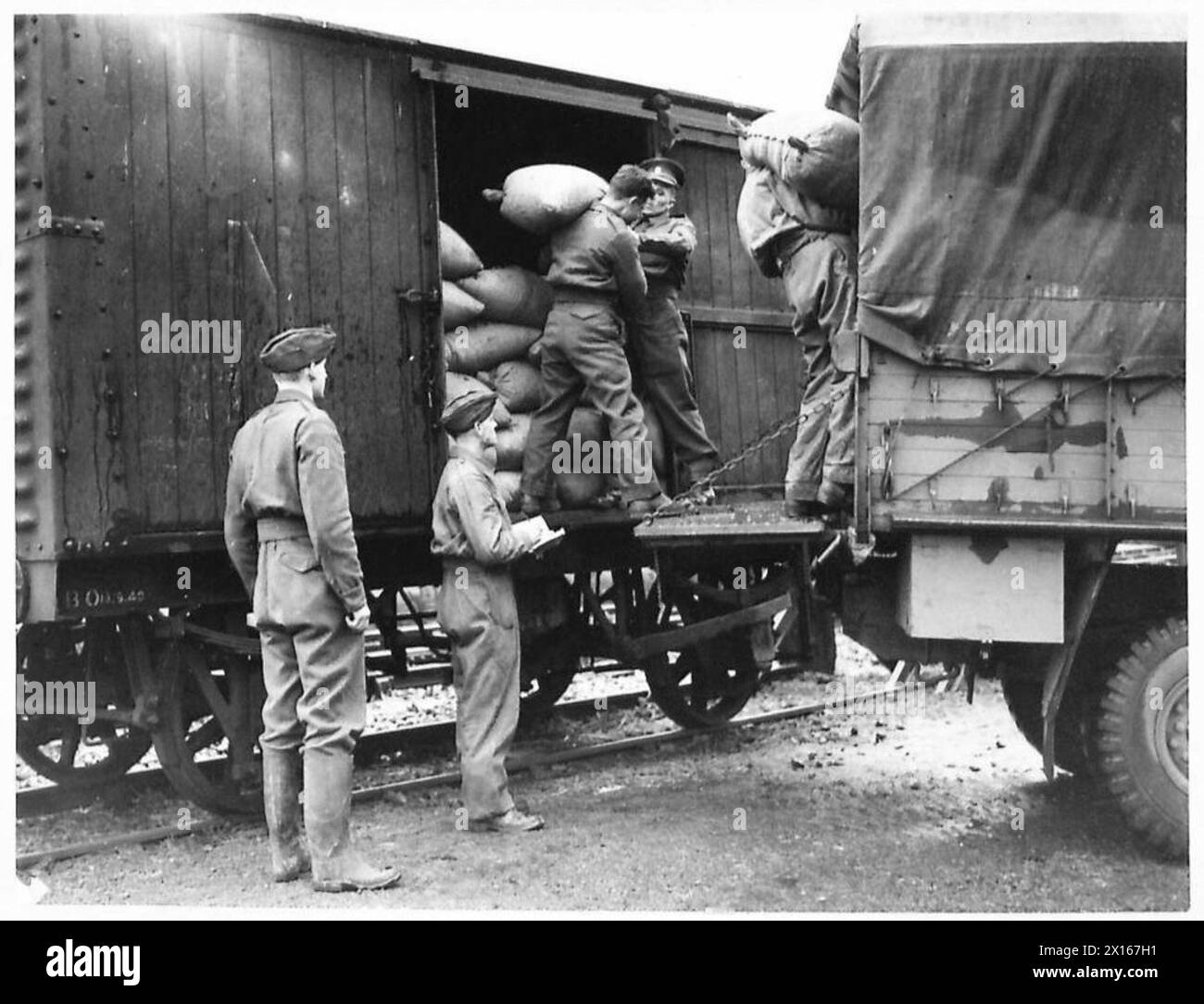 Soldiers unload bags of rice from a truck onto an Army lorry to supply ...