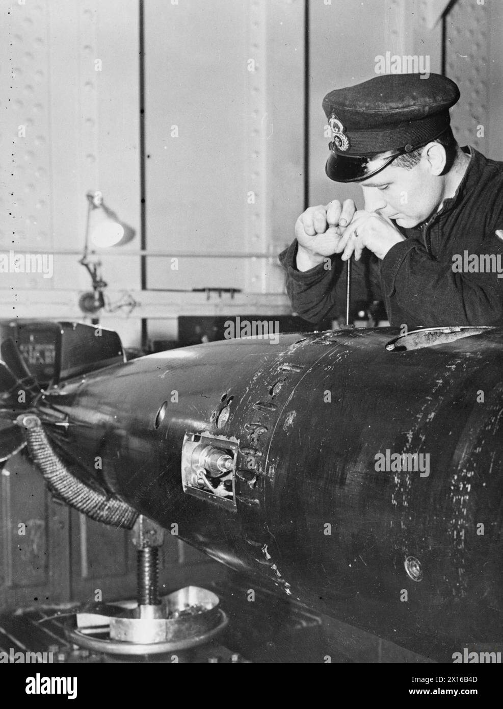 A torpedoman aboard HMS Tyne adjusts the tail of a torpedo being ...