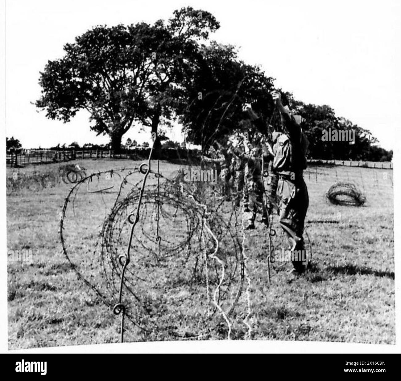 R.A.F. personnel lay a third coil of triple concertina Dannert wiring ...