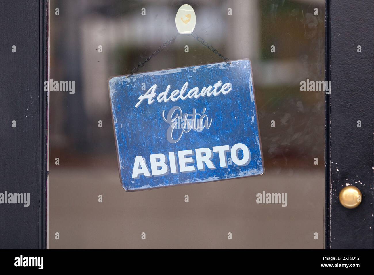 Open sign with written in it in Spanish: "Adelante, está abierto ...