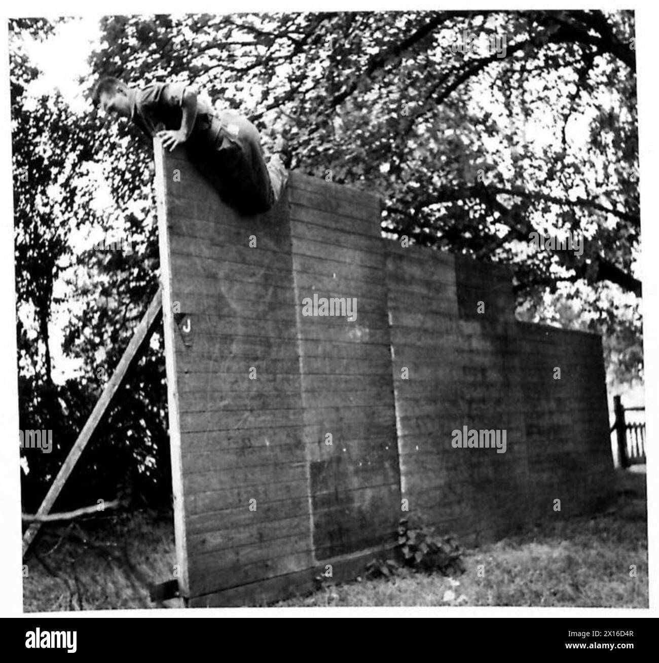 A soldier climbs over a palisade during exercises at the War Office ...