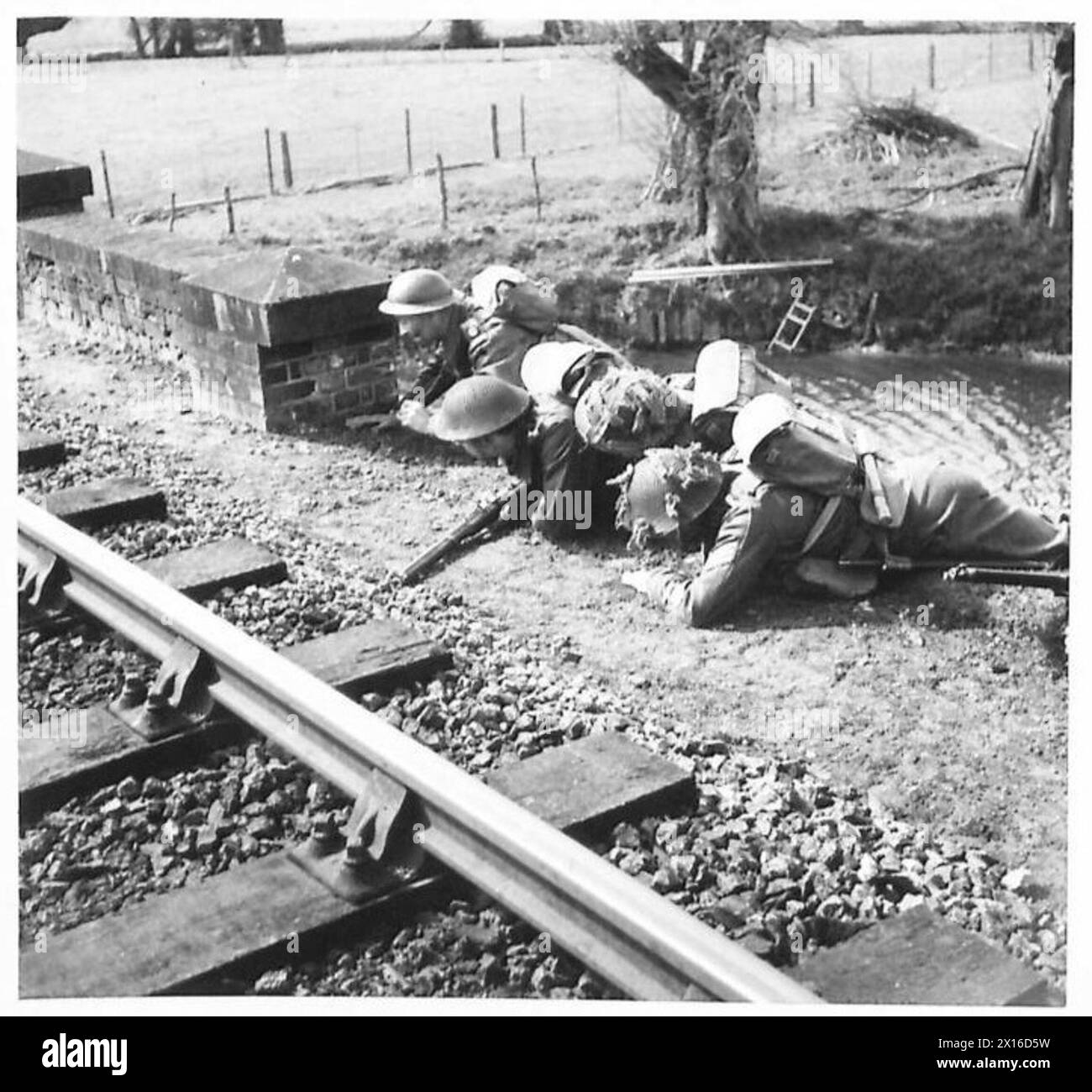 An advanced patrol positions itself by the parapet of a river bridge ...