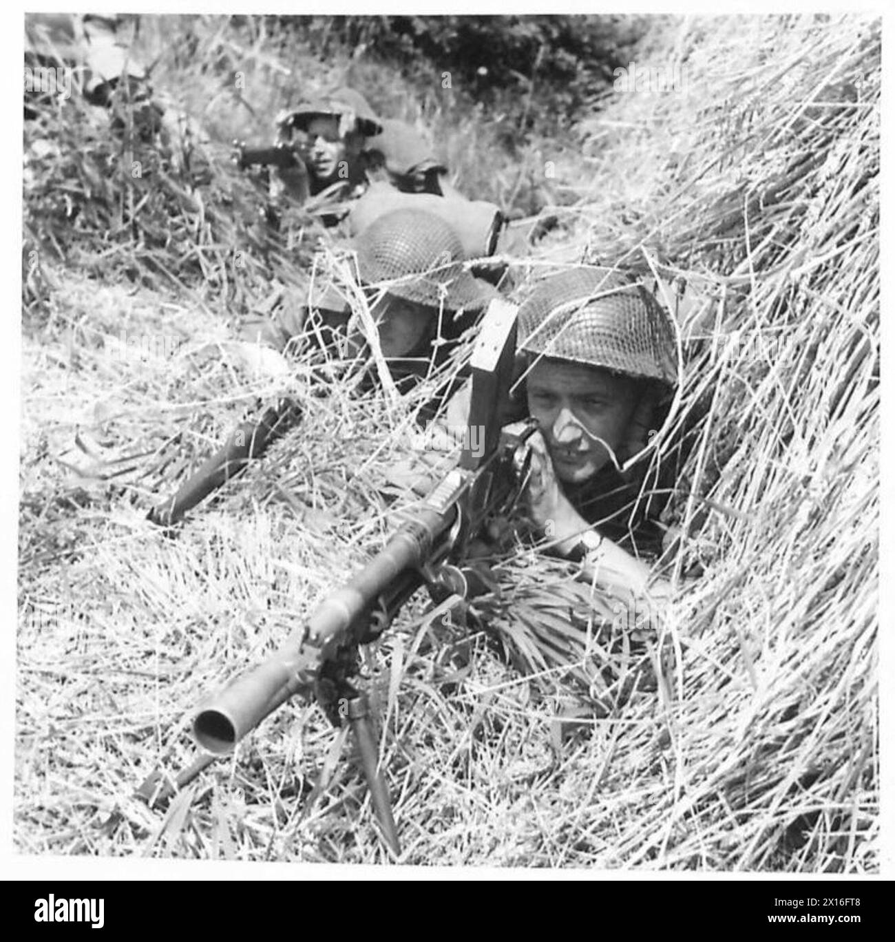 Neutral correspondents observe a Bren gunner concealed beneath a stack ...