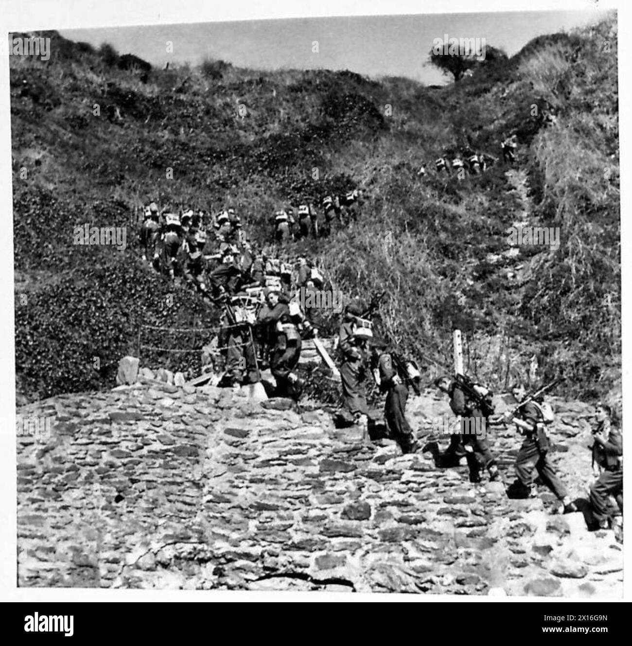 British Army soldiers climb a steep hillside while carrying full ...