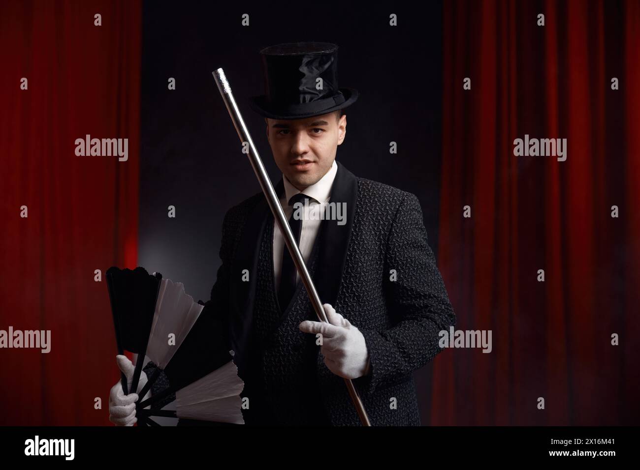 Magician performing miracle trick on stage using fan and cane Stock ...