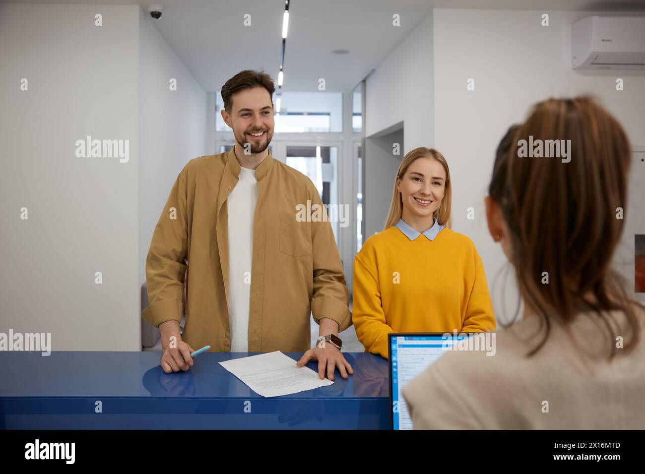 Happy man and woman couple signing document at modern clinic reception ...