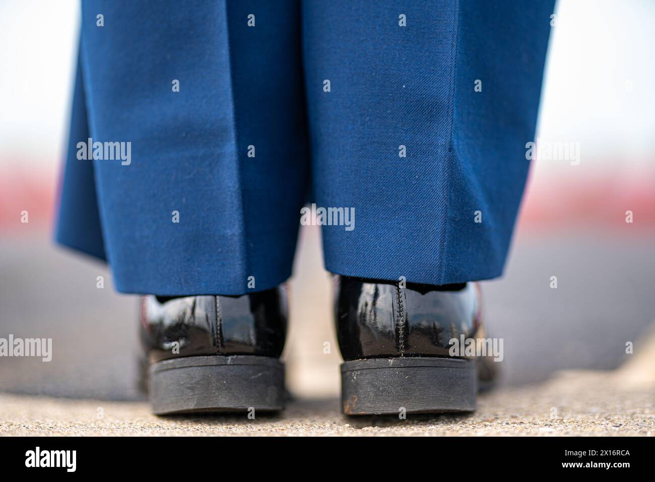 A pair of polished black shoes with a blue stripe on the side. The ...