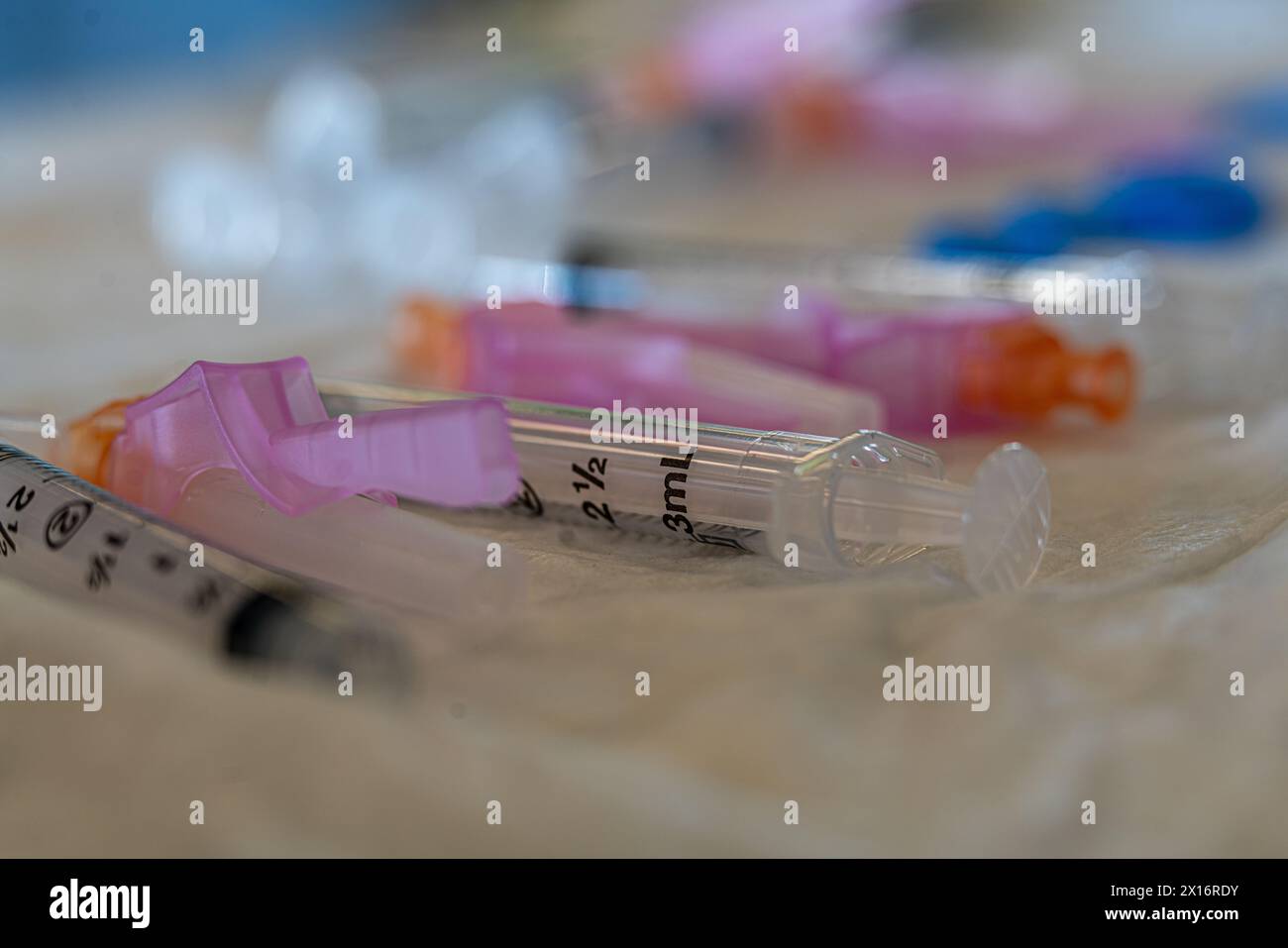 A bunch of syringes are laying on a table. The syringes are of ...