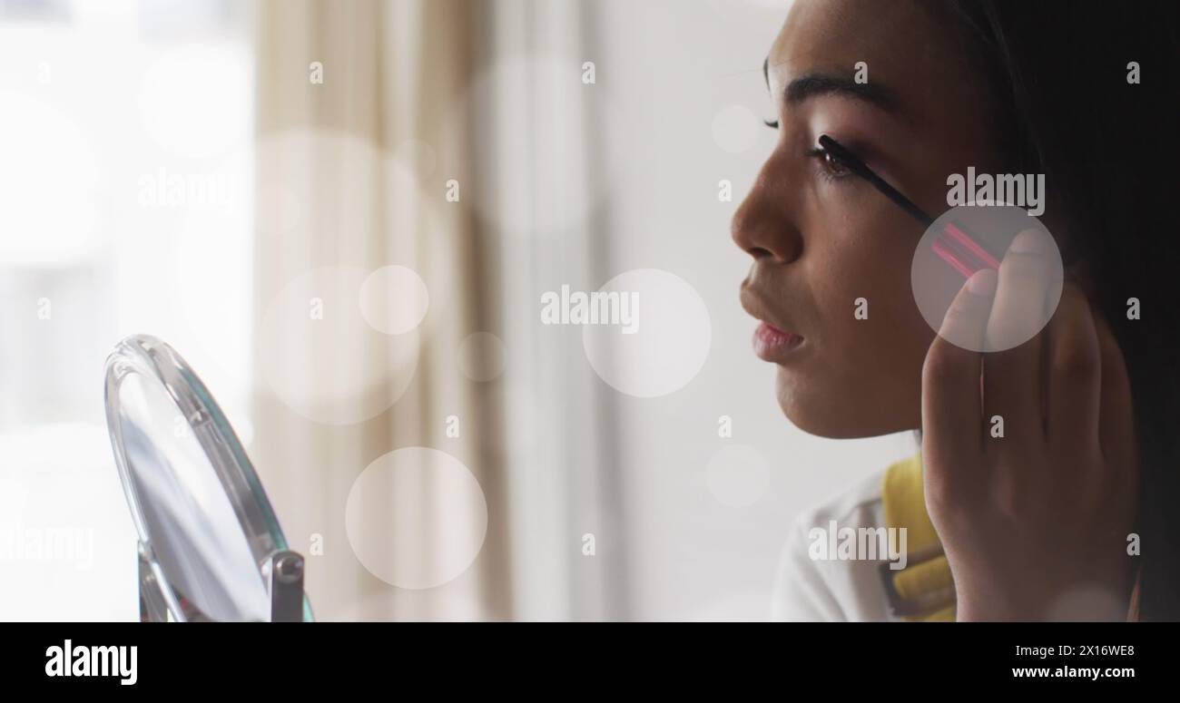 Image of light spots over biracial woman applying mascara Stock Photo ...