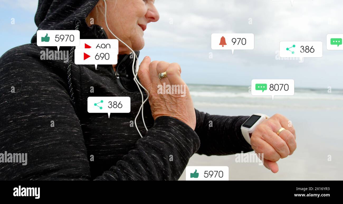 Image of notification bars over senior caucasian woman with headphone using smartwatch at beach ...