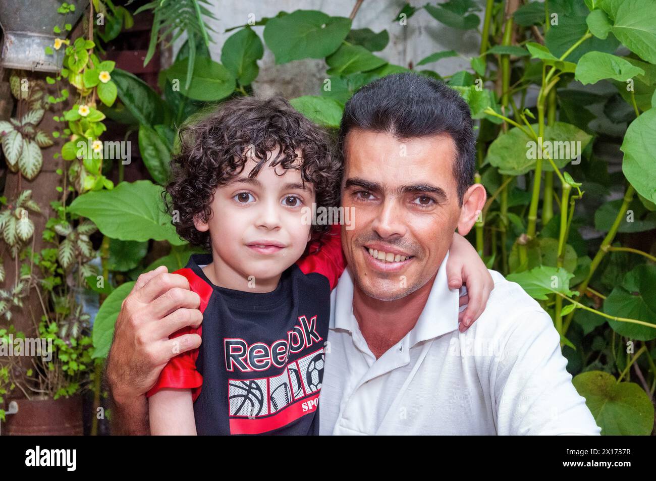 Child boy and uncle in backyard of house. Portrait of real Cuban people ...