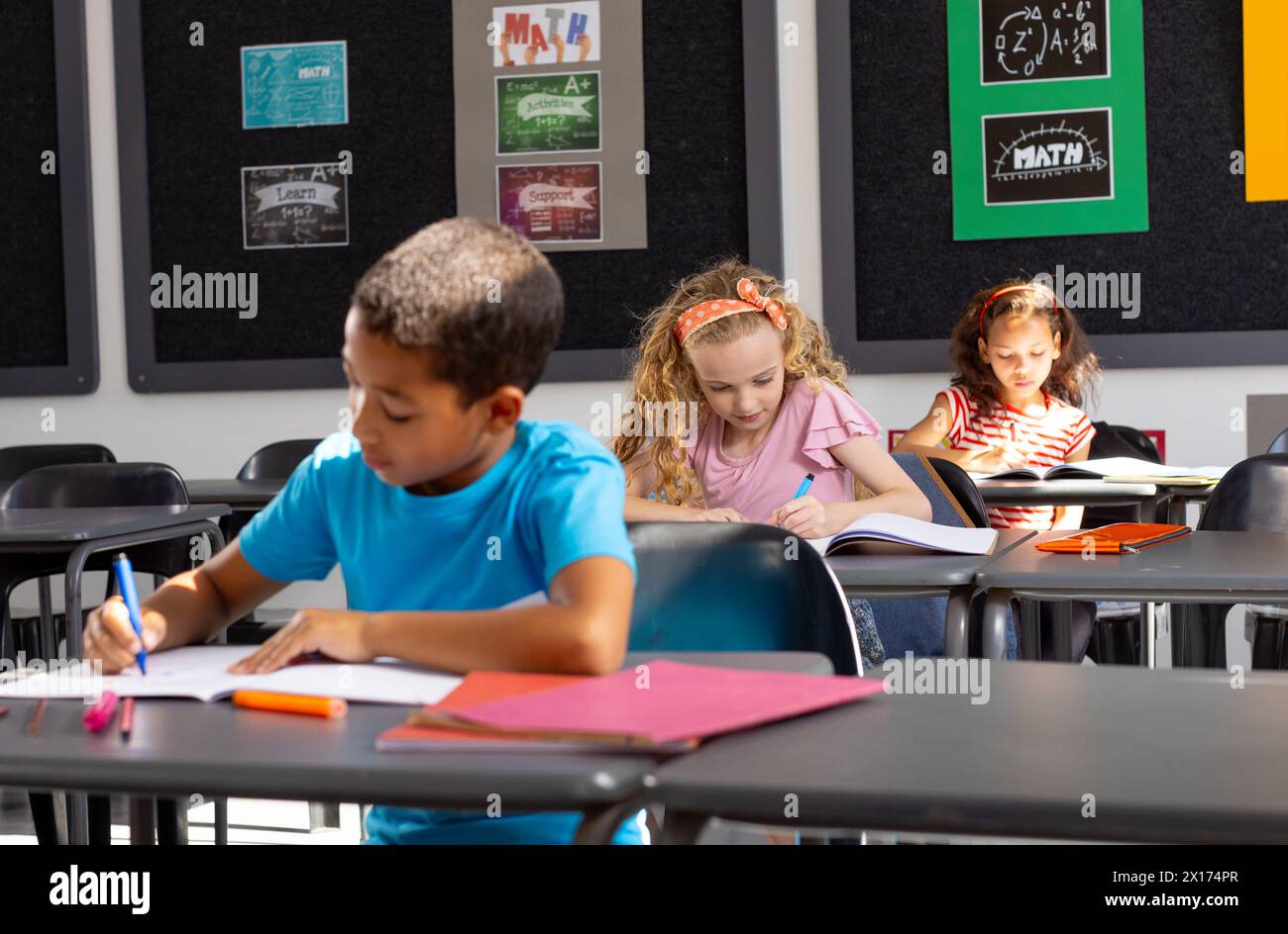 In school, diverse group of young students is focusing on their work in ...