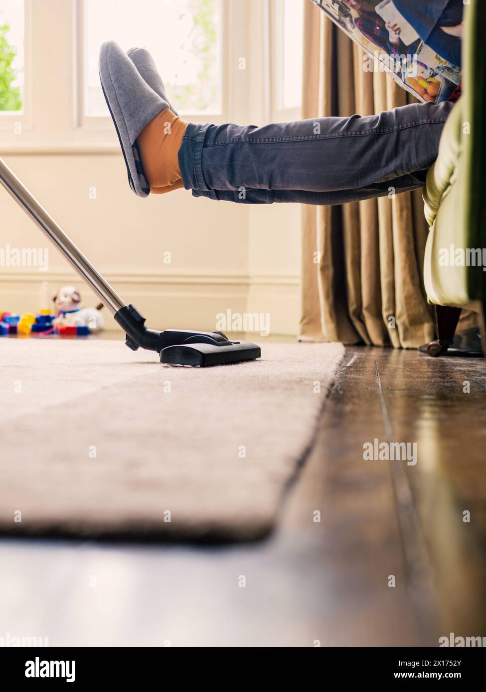 Man lifting feet whilst vacuum clean underneath Stock Photo - Alamy
