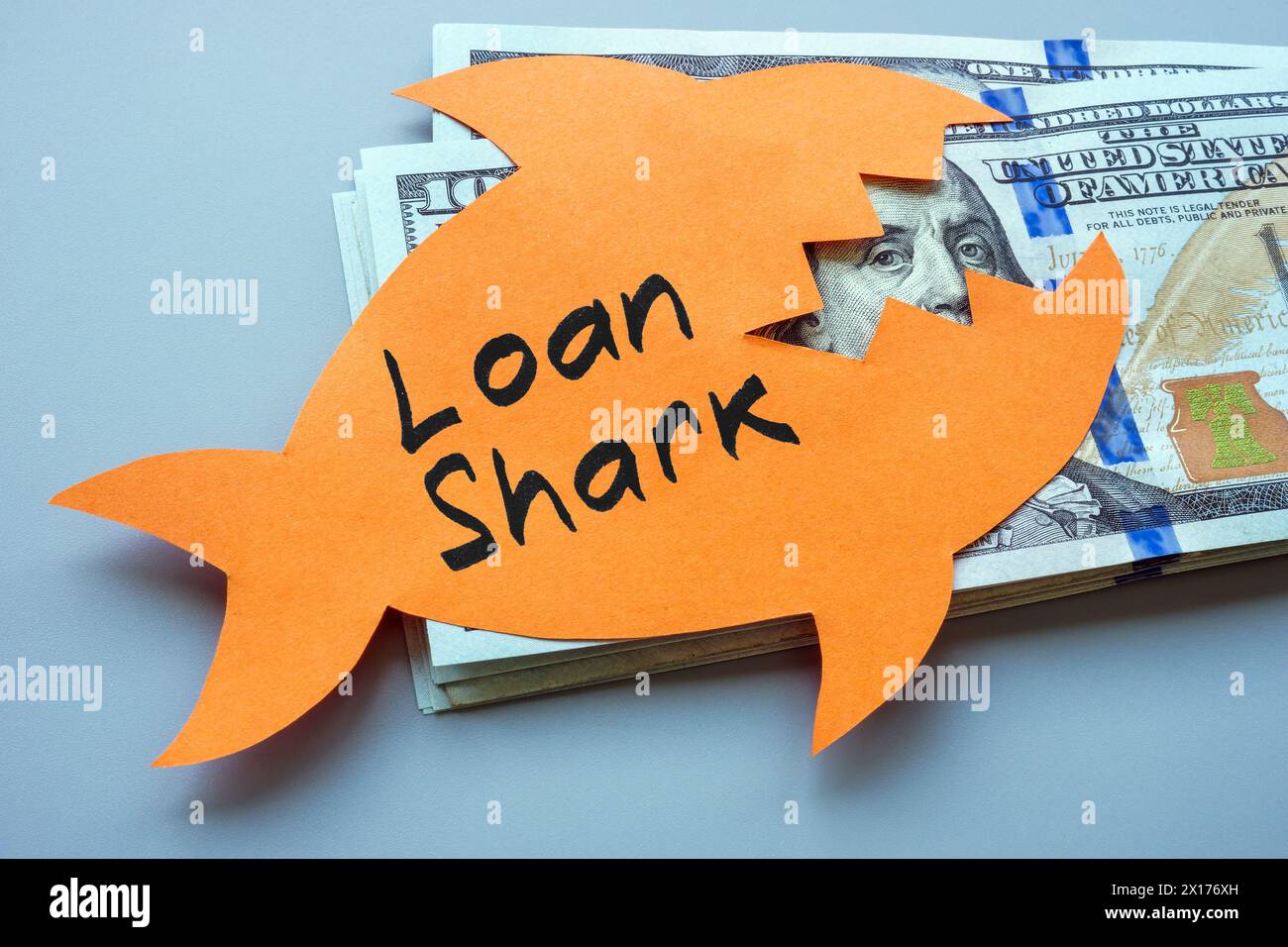 A stack of money and a paper fish with an inscription loan shark Stock ...