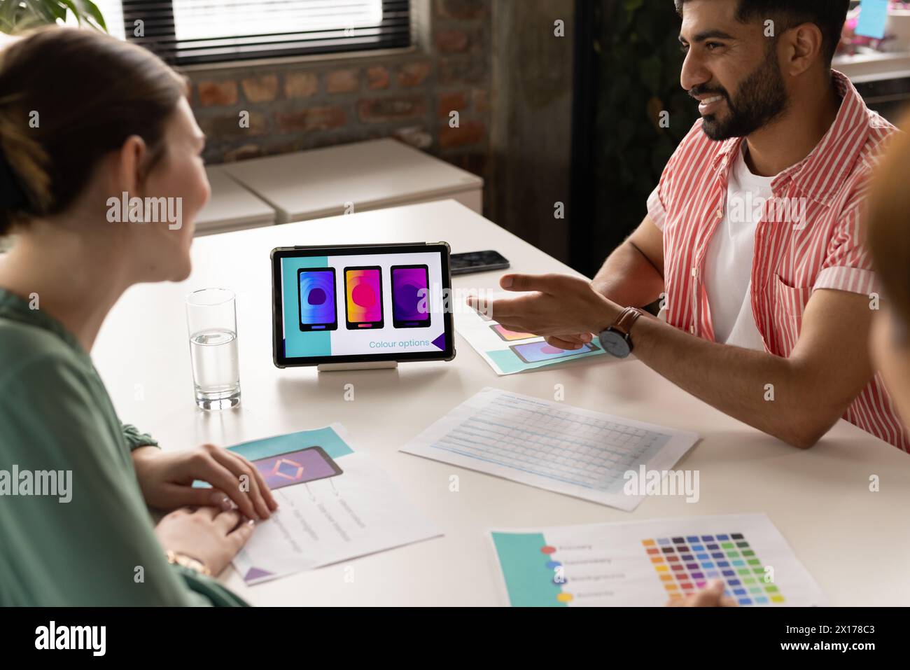 Diverse team discussing app design in a modern business office, tablet ...