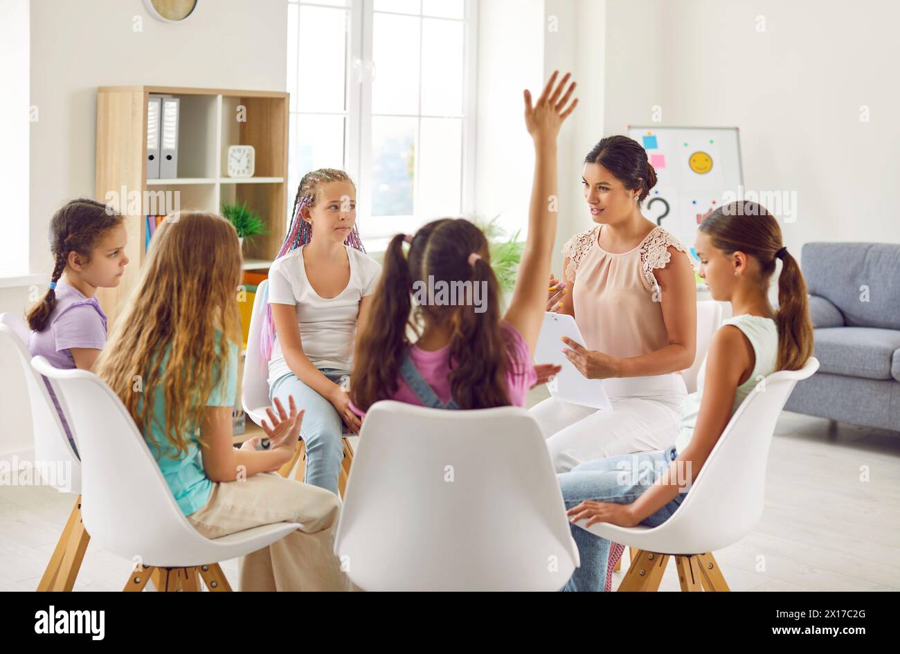 Group of school children girls sitting in a circle with psychologist ...