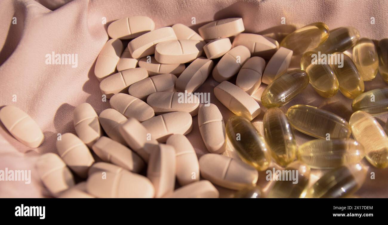 Vitamins and omega 3 fish oil on the natural wood background with pink ...