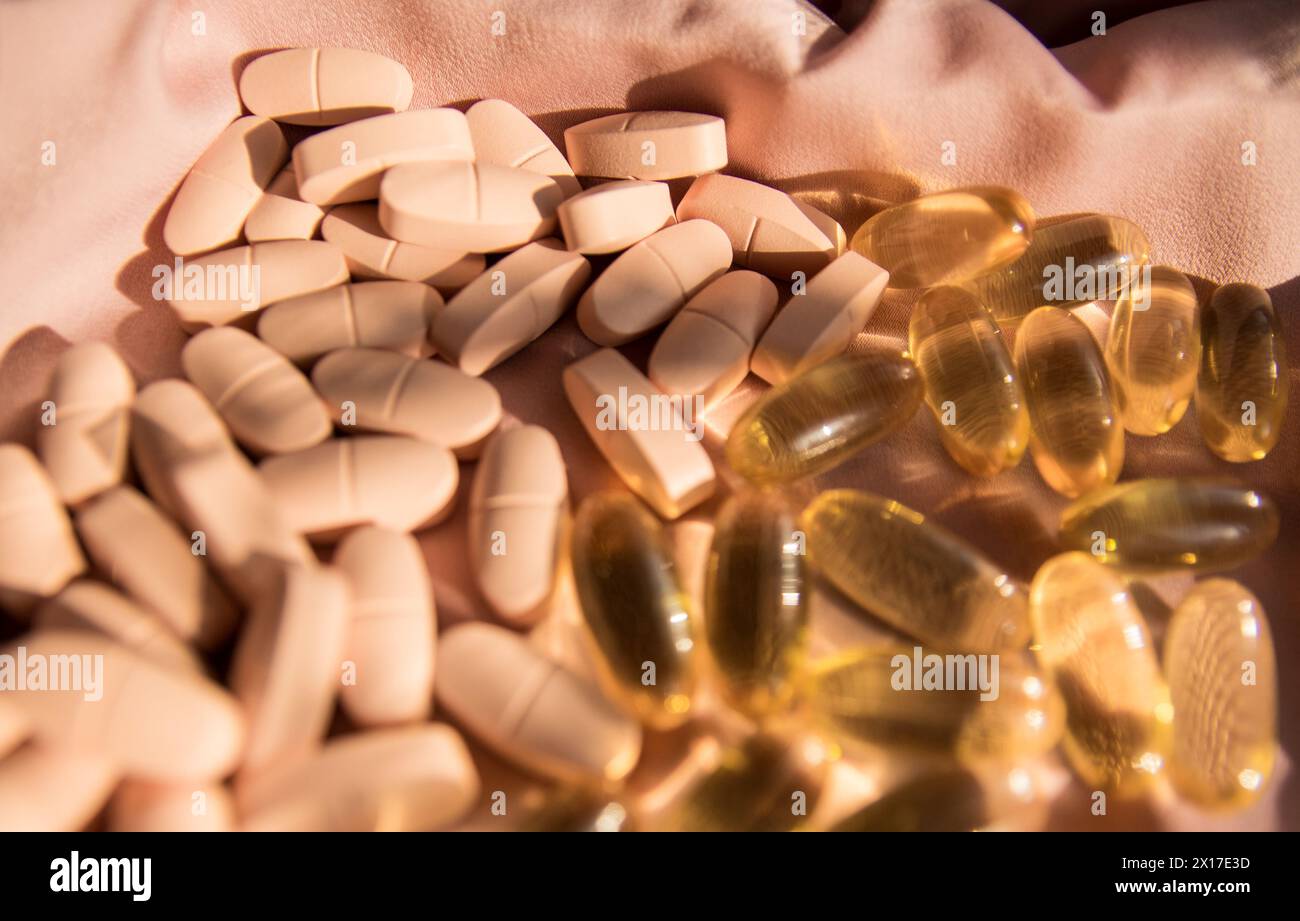 Vitamins and omega 3 fish oil on the natural wood background with pink ...