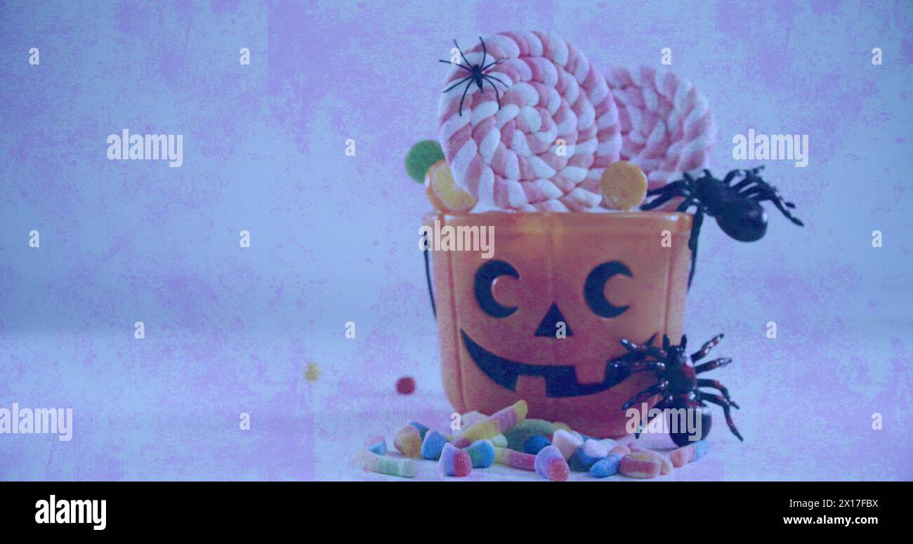 Spiders and candies in halloween scary pumpkin bucket against textured ...