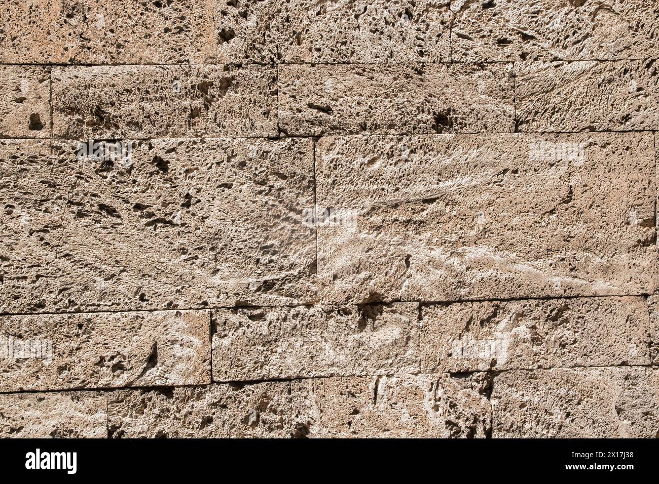 Stone wall of limestone bricks with spongy surface closeup as stone ...