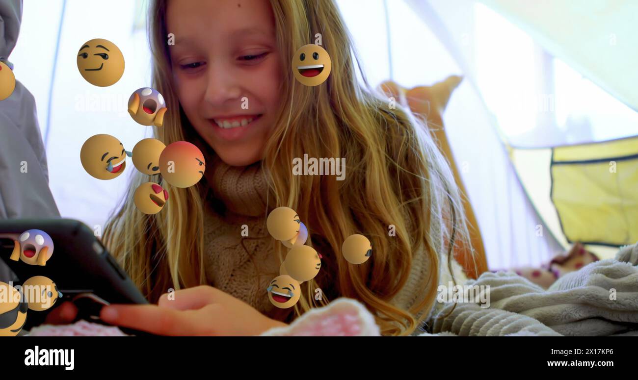 Image of multiple floating emoticons on caucasian girl using cellphone ...
