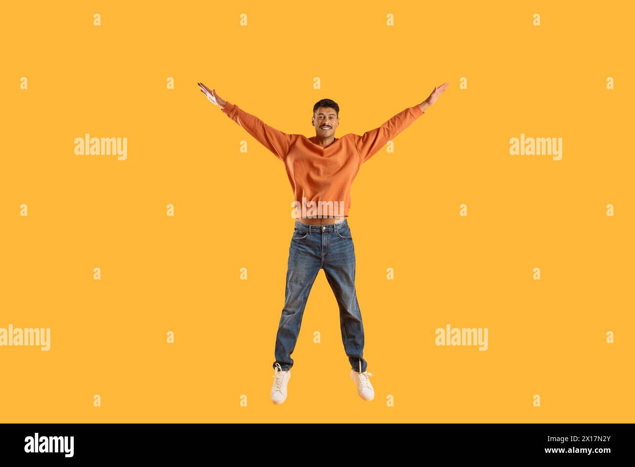 Excited man jumping with joy against yellow background Stock Photo - Alamy