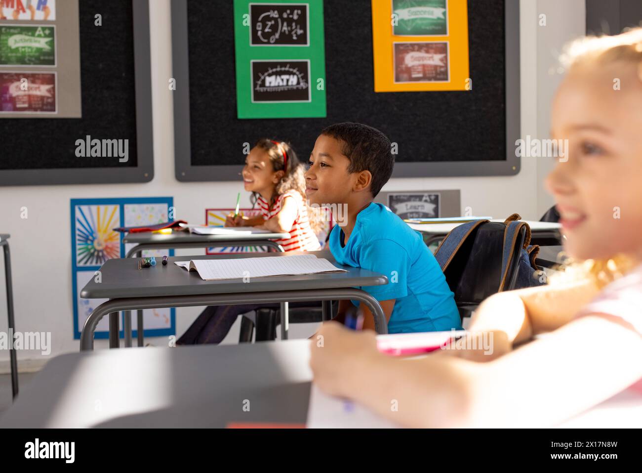 In school, diverse young students focusing on learning in the classroom ...