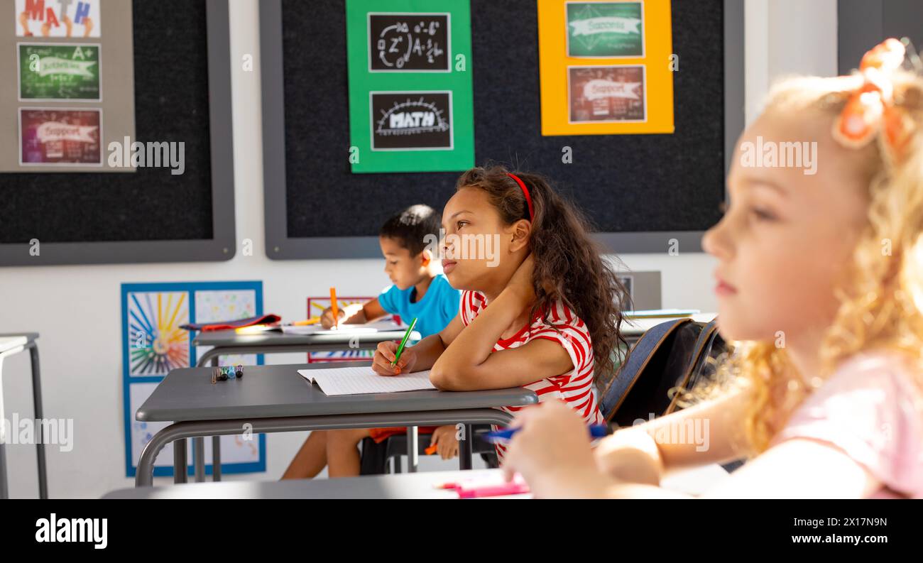 In school, diverse group of young students focusing on their work in ...