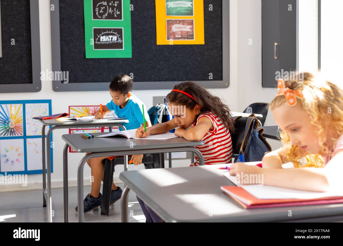 In school, diverse group of young students focusing on their work in ...