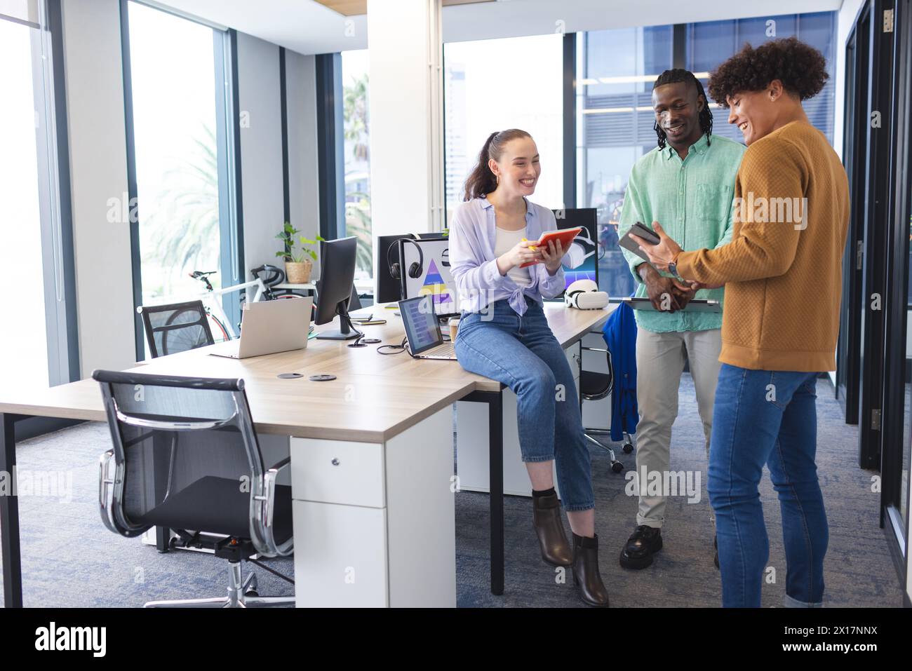 Diverse team sharing ideas in office, Caucasian woman showing tablet ...