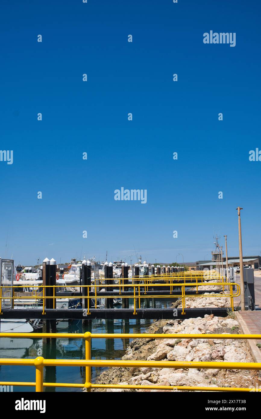 Jetties with yellow handrail and mooring posts reflecting in the water ...