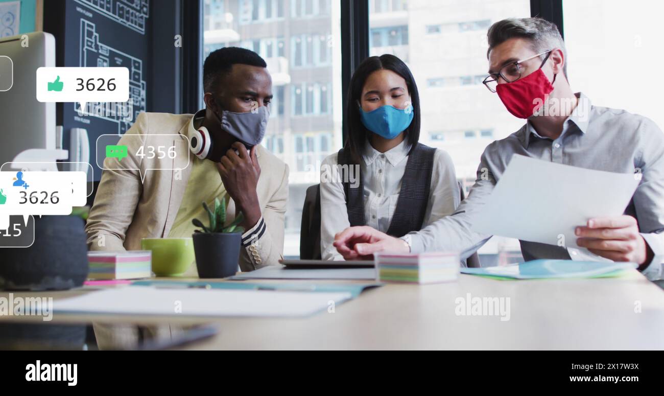 Image of social media icons over diverse colleagues wearing face masks ...