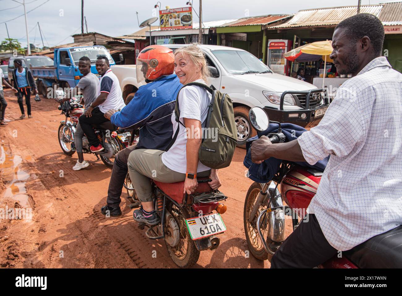Women passenger on motorcycle navigates muddy Entebbe streets in Uganda ...