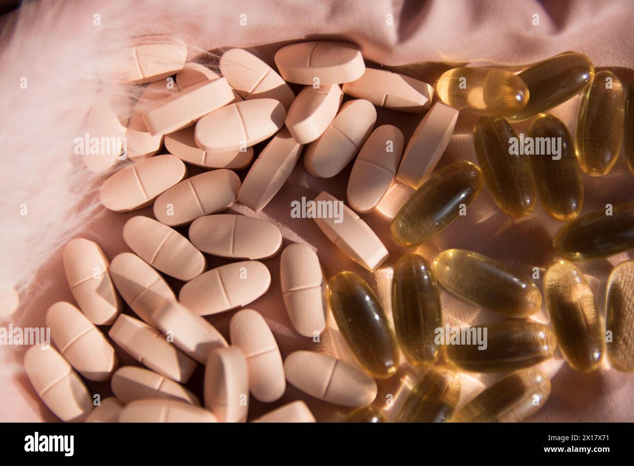 Vitamins and omega 3 fish oil on the natural wood background with pink ...