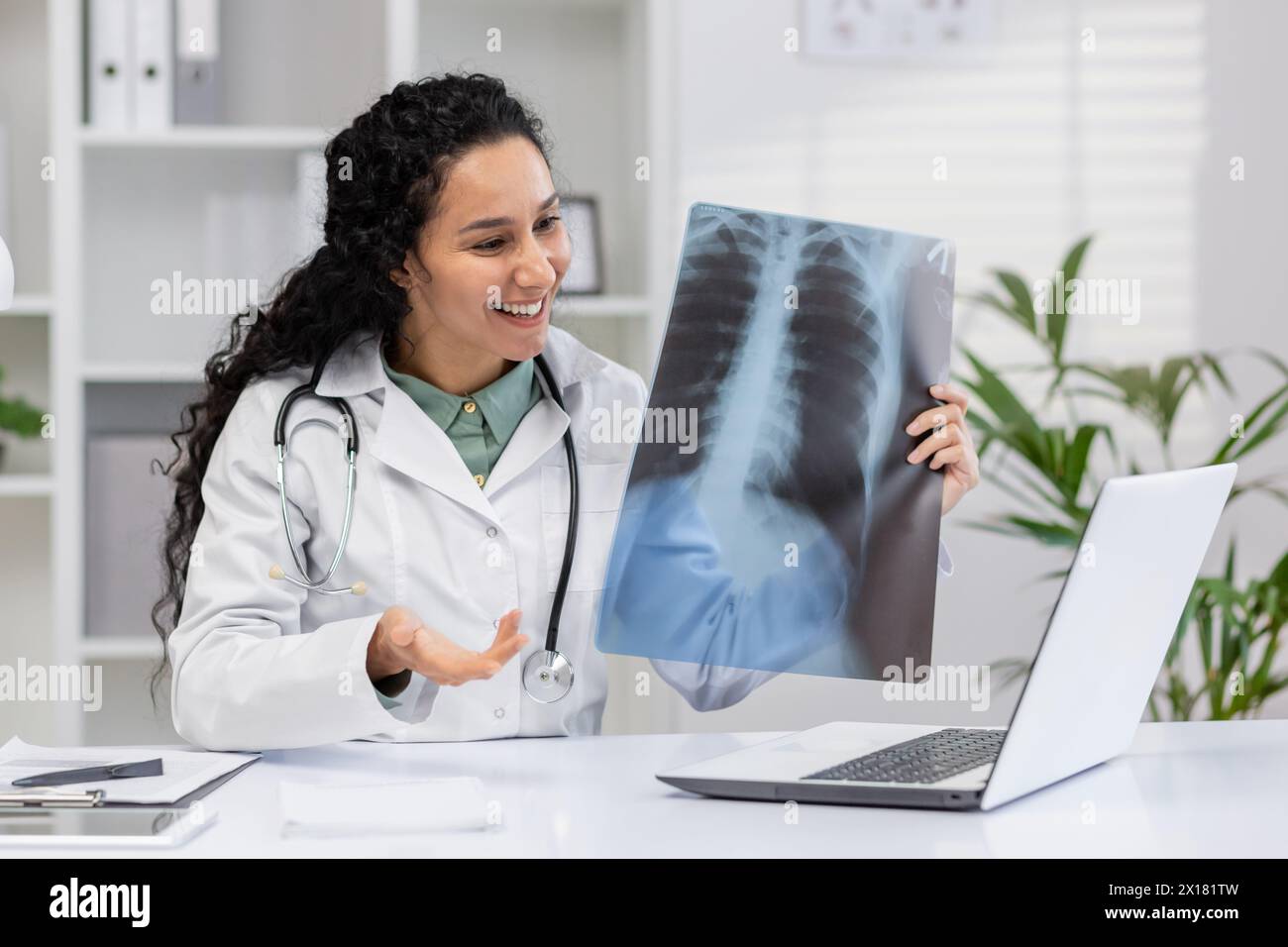A cheerful female radiologist analyzes a chest X-ray in her medical ...