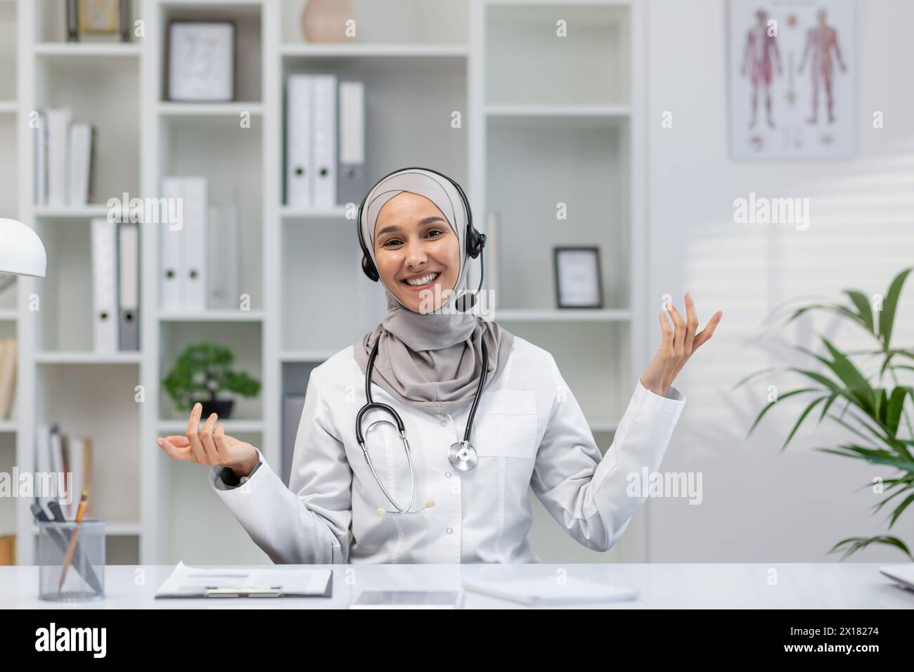Smiling female doctor wearing a hijab and headset communicates with a ...