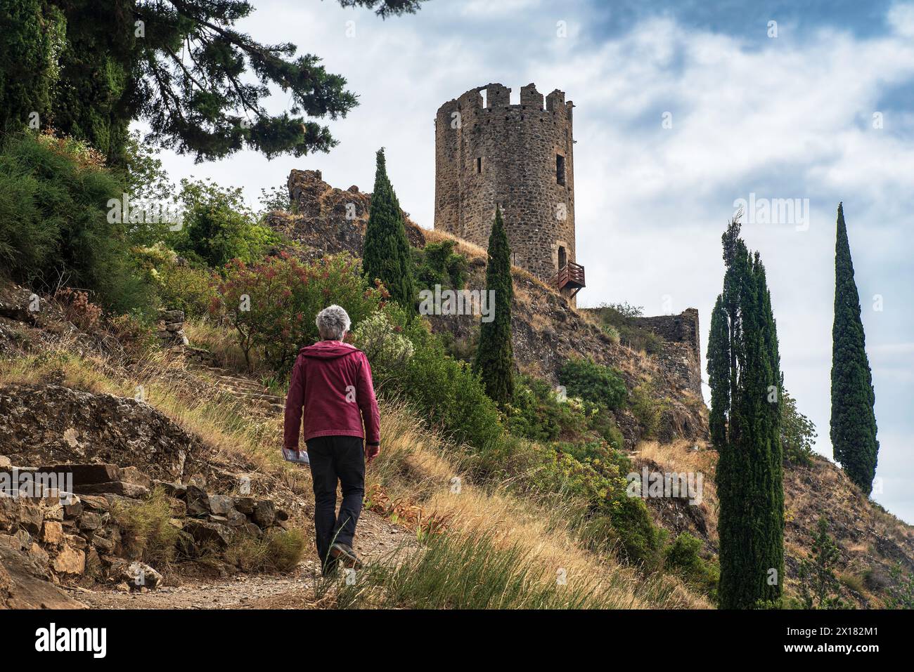 A tourist in the ruins of the medieval castle of Lastours, in the ...