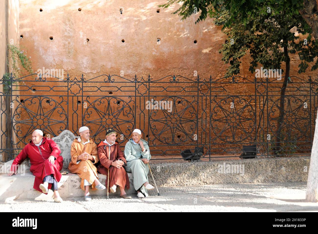 Chefchaouen, men in traditional dress chatting while sitting outside ...