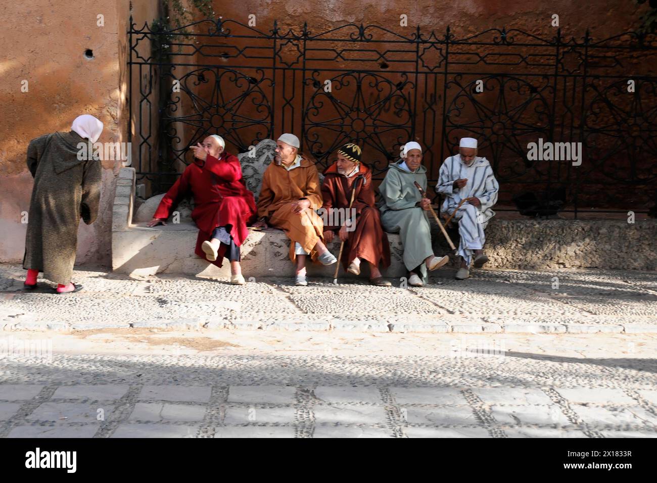 Chefchaouen, A group of people sitting in front of an orange-coloured ...