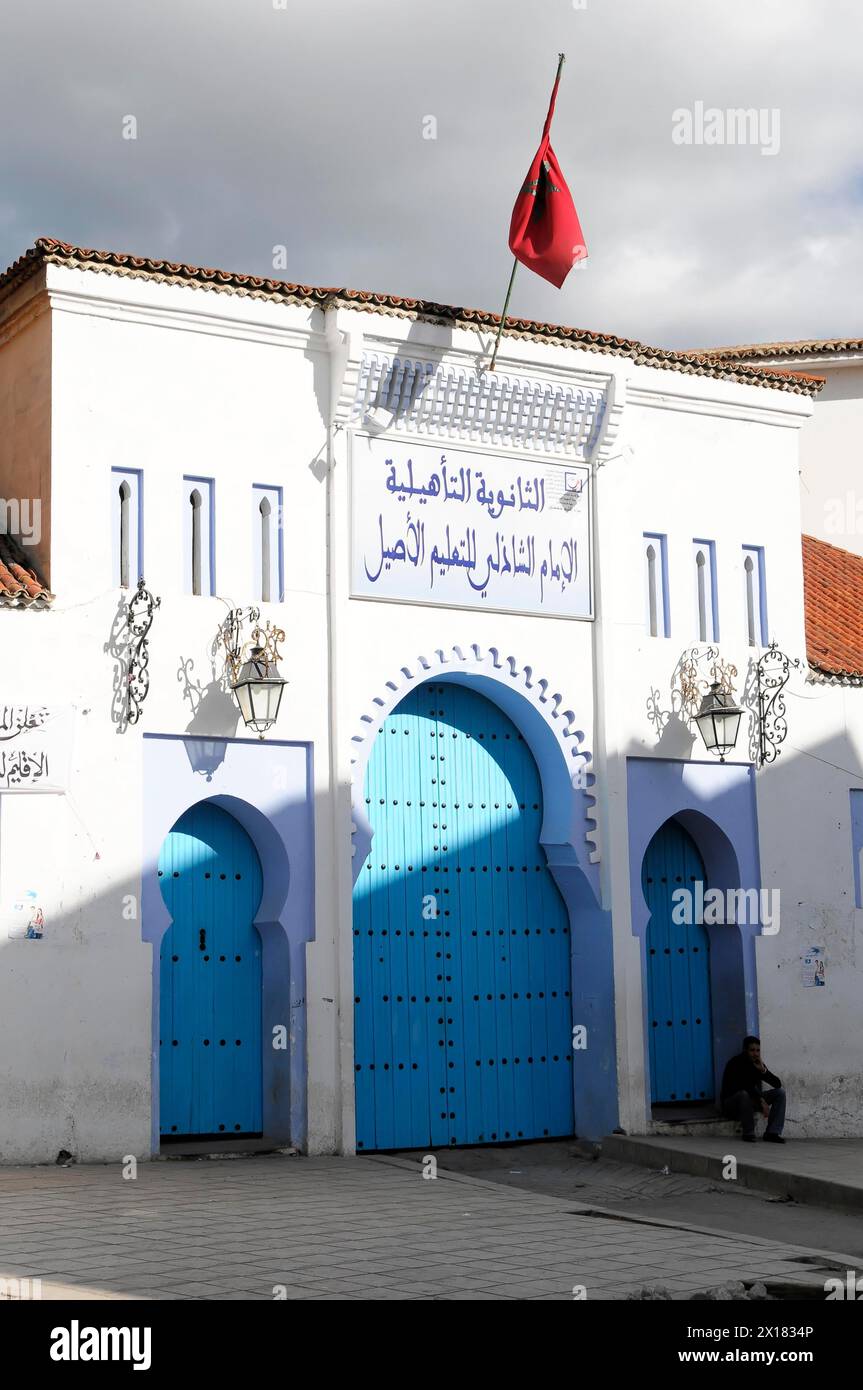 Chefchaouen, White Moroccan building with blue gates under a cloudy sky ...