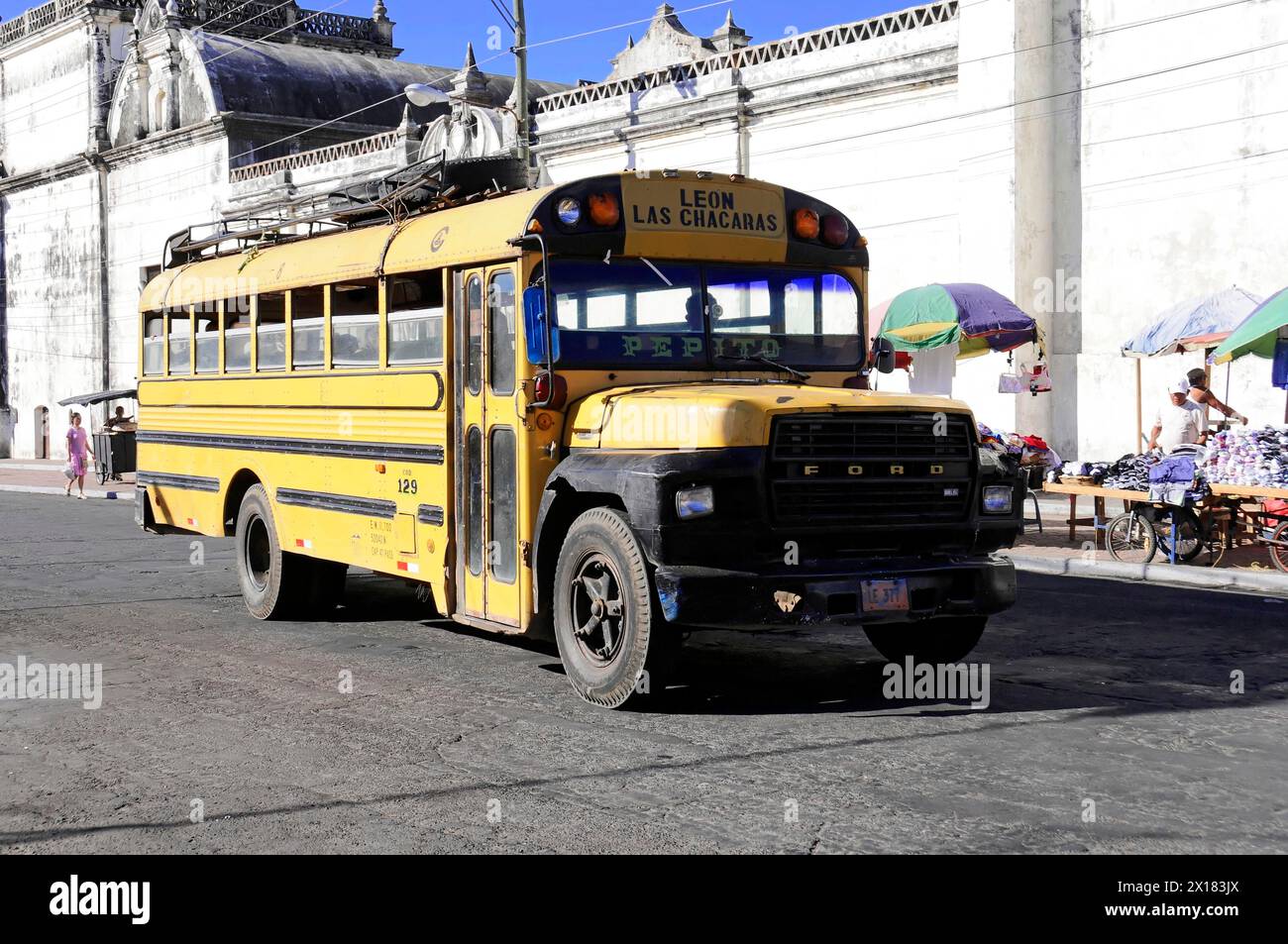 Leon Nicaragua, Yellow school bus drives on a street past historic ...
