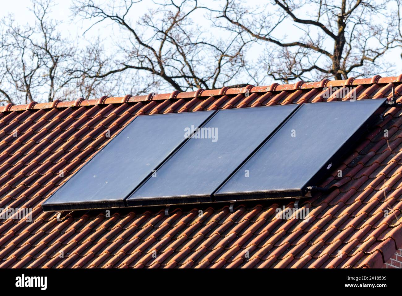 A portrait of black solar panels installed on an orange tiled roof ...