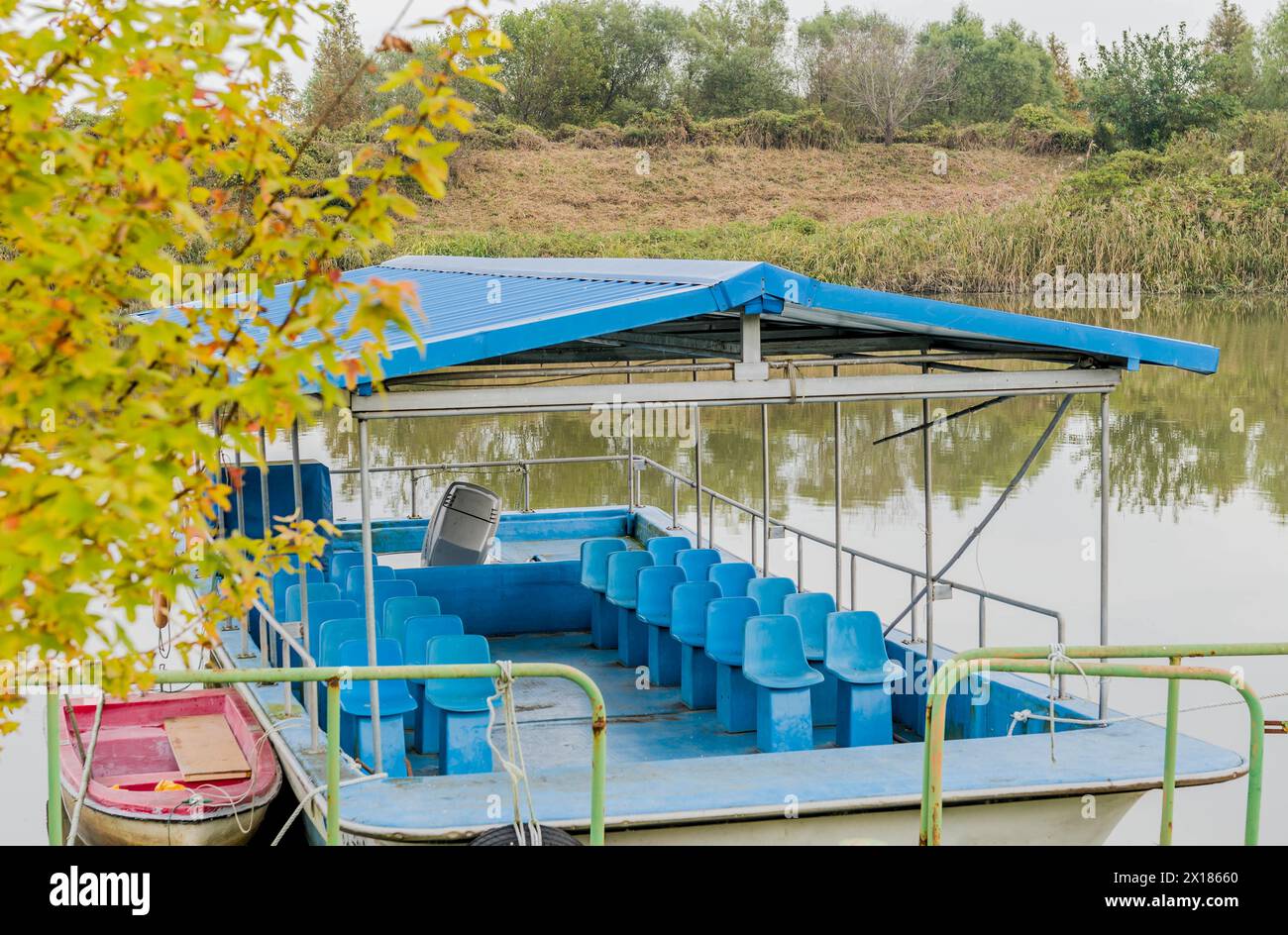 Old flat bottom tour boat moored at riverside dock in wilderness park ...